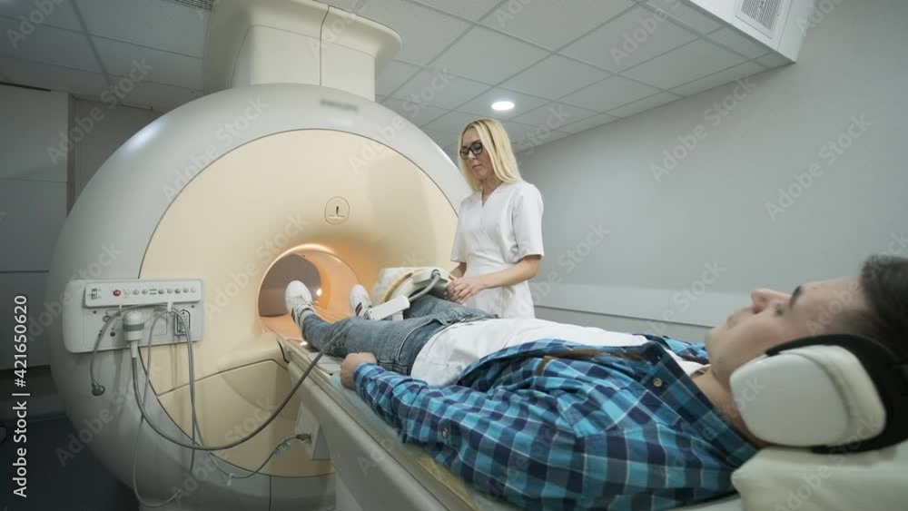 Woman doctor makes knee-joint MRI scanning. Young man patient on ...