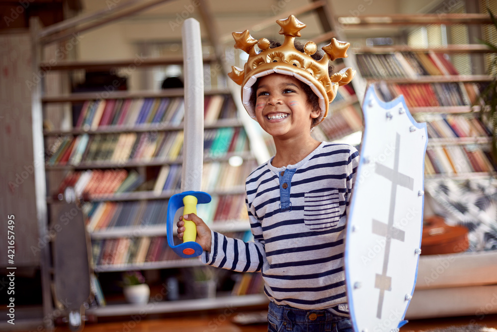 A cute little boy dressed as knight is posing for a photo while playing ...