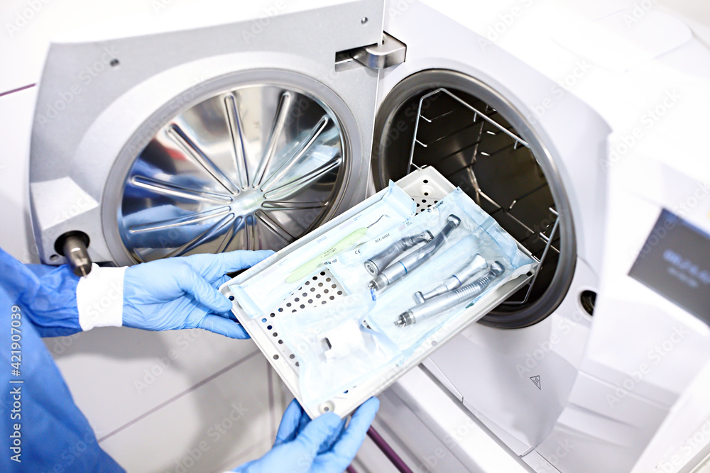 Nurse putting instruments in special craft paper bags into autoclave ...