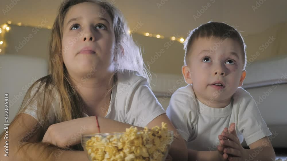 Cute little kids while watching TV. Two children watching TV, eating ...