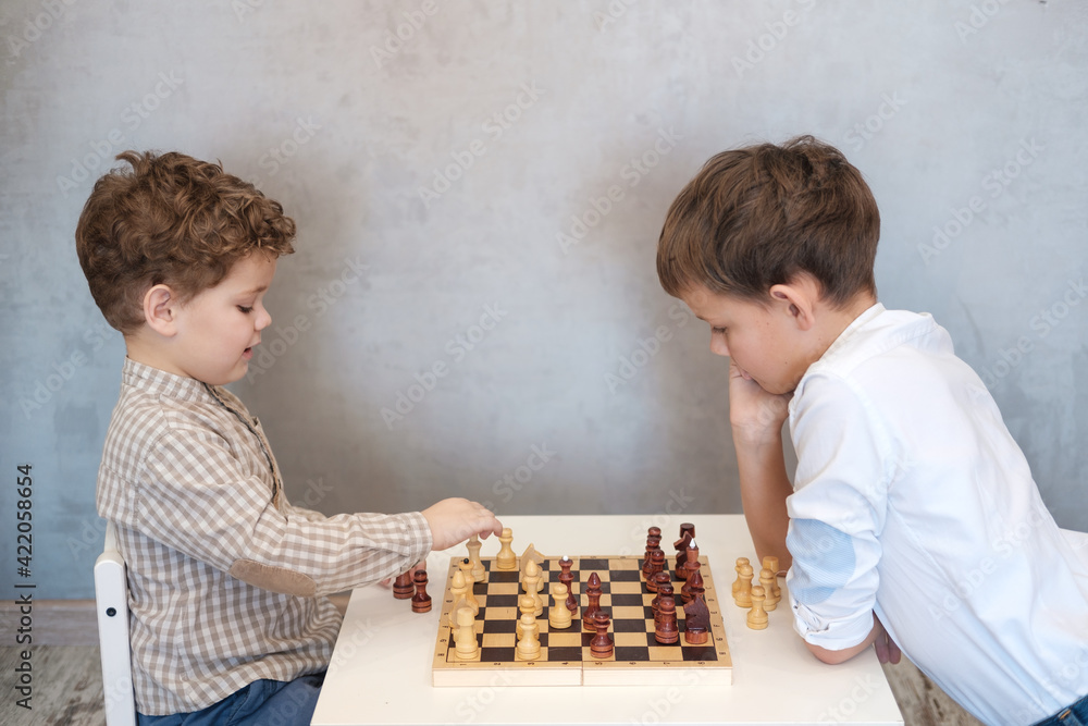 two brothers play chess at a table. children play a game of chess ...