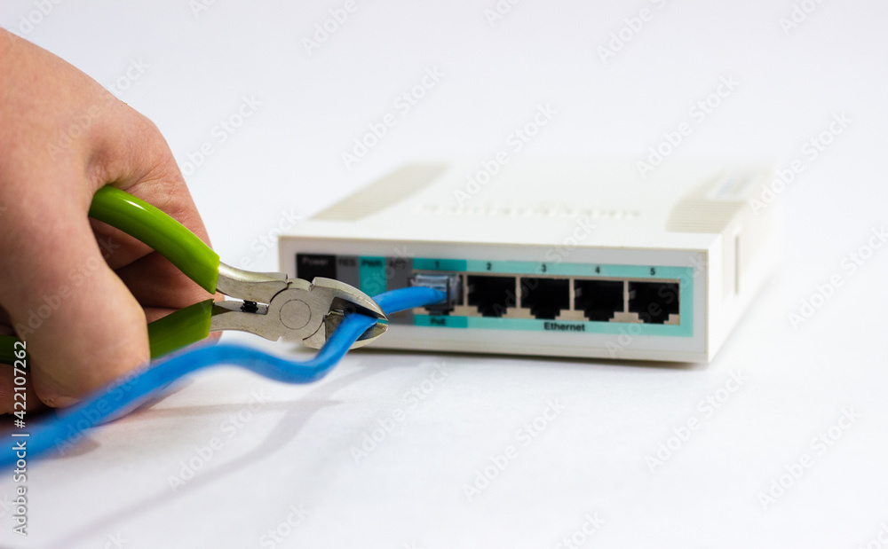 Cuts cable on router. Man cuts cord of Wi-Fi router. White router with ...