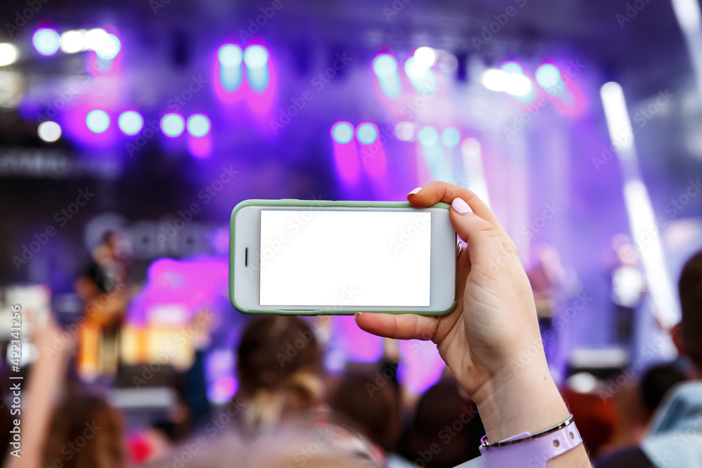 Hands holding a mobile smartphone on a live concert with a blank white ...