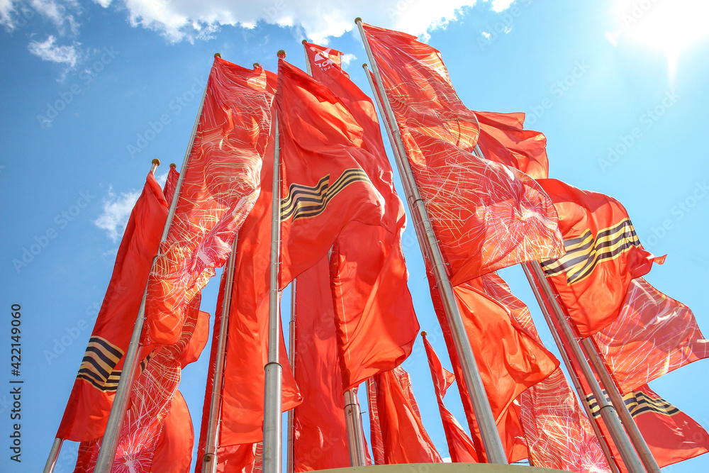 Group of red flags with george ribbons swings on flagpoles. Blue sky ...
