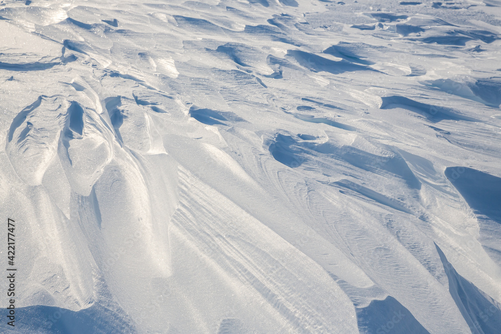 Fotka „Snow texture. Wind sculpted patterns on snow surface. Wind in ...
