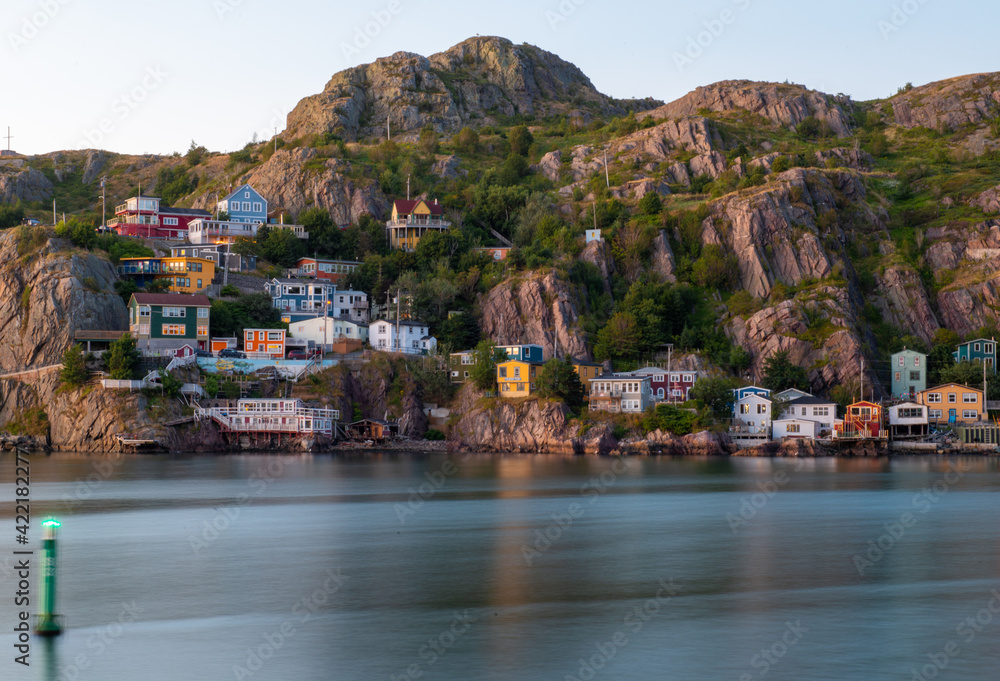 Colourful wooden houses built on a hillside or on a cliff with the deep ...