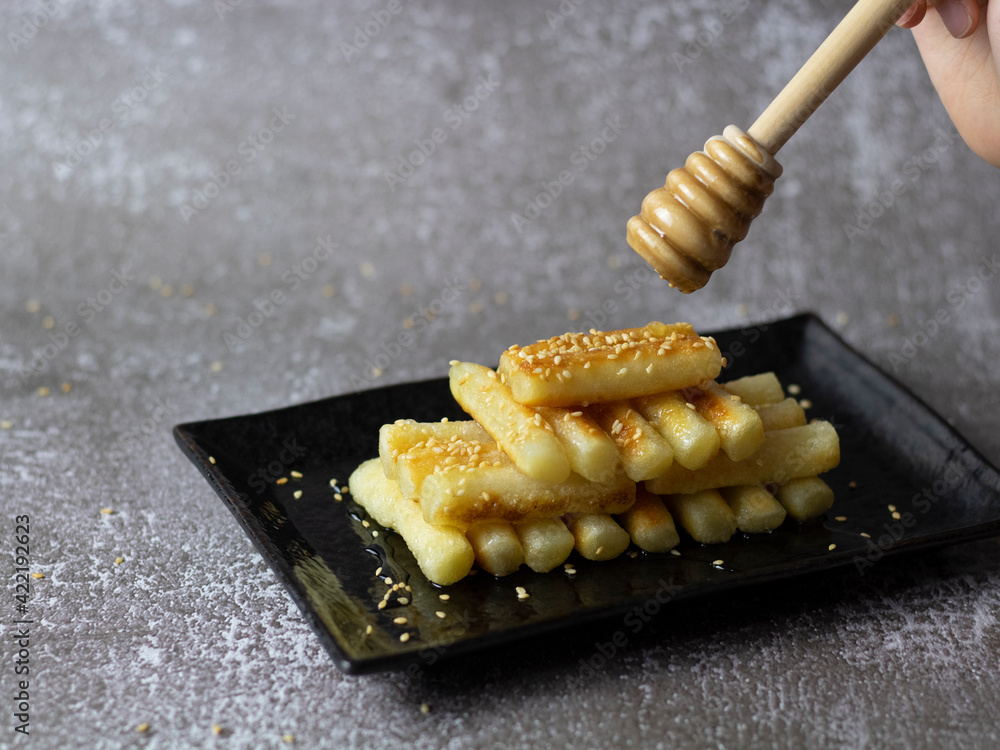 Korean Rice Cakes with Honey (Garaetteok). Dripping honey on tteokbokki ...