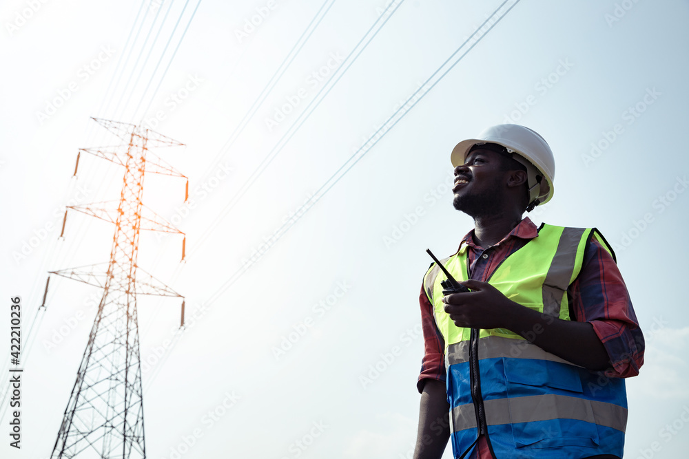 Electrical Africa American engineer with high voltage electricity pylon ...