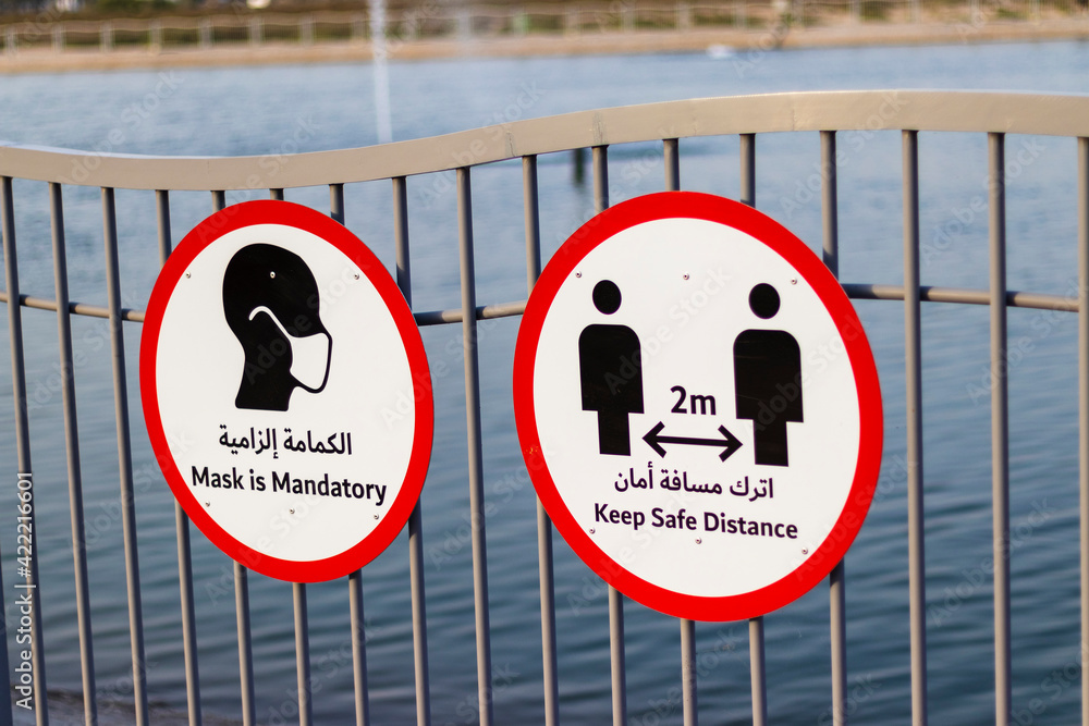 Covid 19 warning signs in Arabic and English languages on the fence of ...