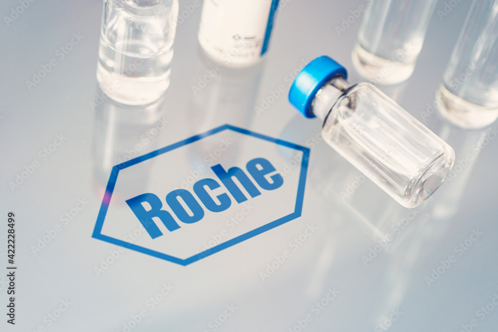 Vials of liquid on a white table and the logo of a large pharmaceutical ...