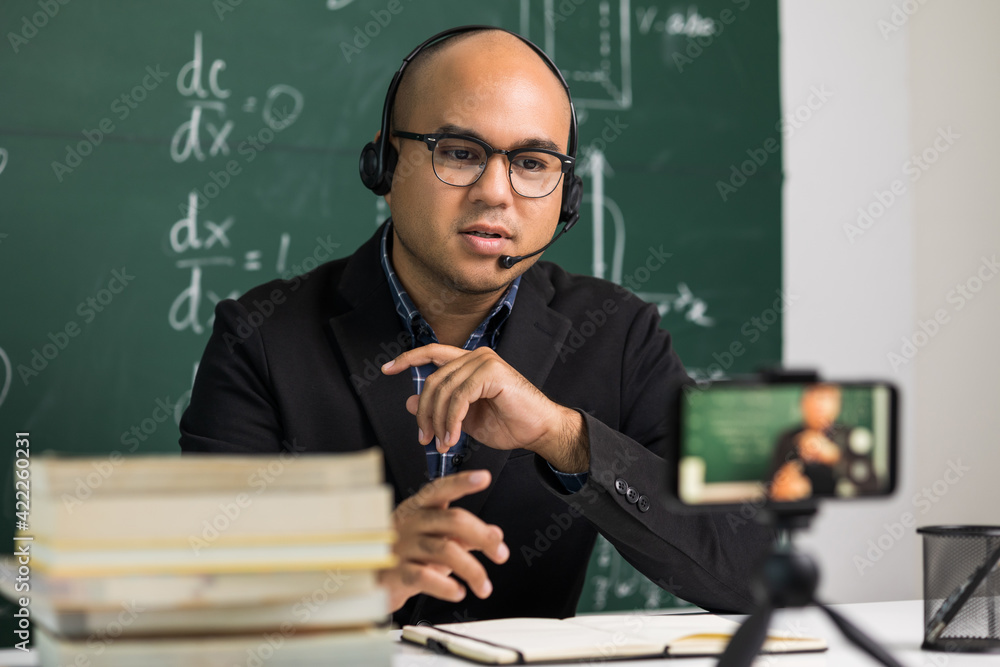 Indian young teacher man sitting wearing headset teaching online video ...