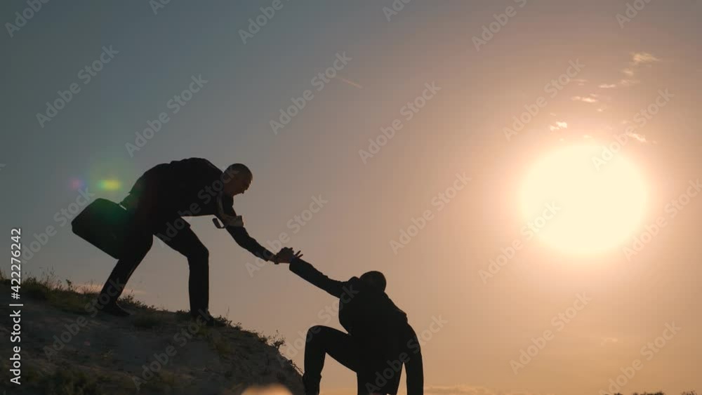 Two businessmen climb to top of mountain. Helping hand in business ...