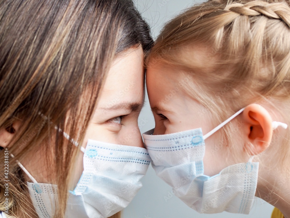 Caring for loved ones. Mother wearing medical mask sitting face to face ...