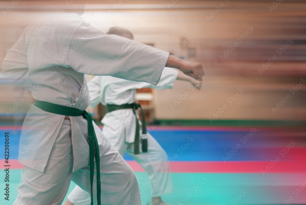 Karate-do training for teenagers. An athlete in a white kimano with a ...
