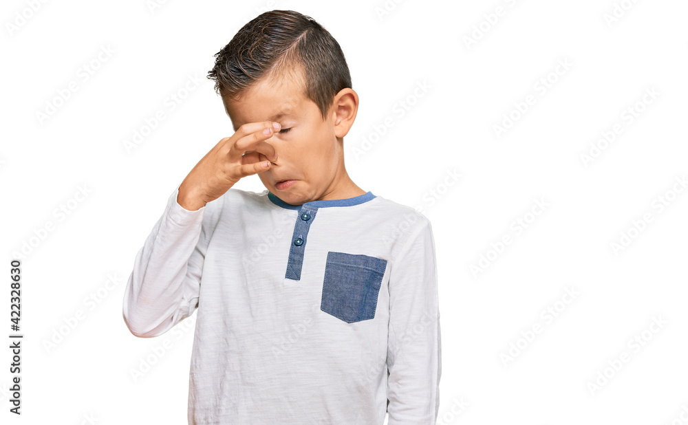 Adorable caucasian kid wearing casual clothes smelling something stinky ...