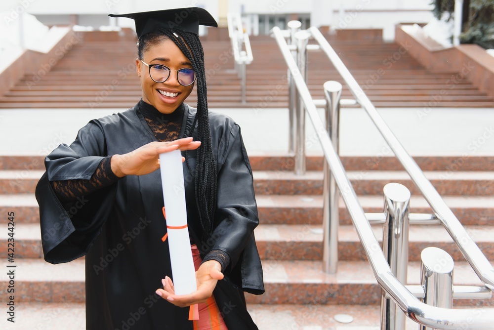 pretty african college student in graduation cap and gown in front of ...