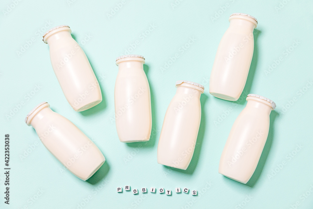 Small bottles with probiotics and prebiotics dairy drink on blue ...
