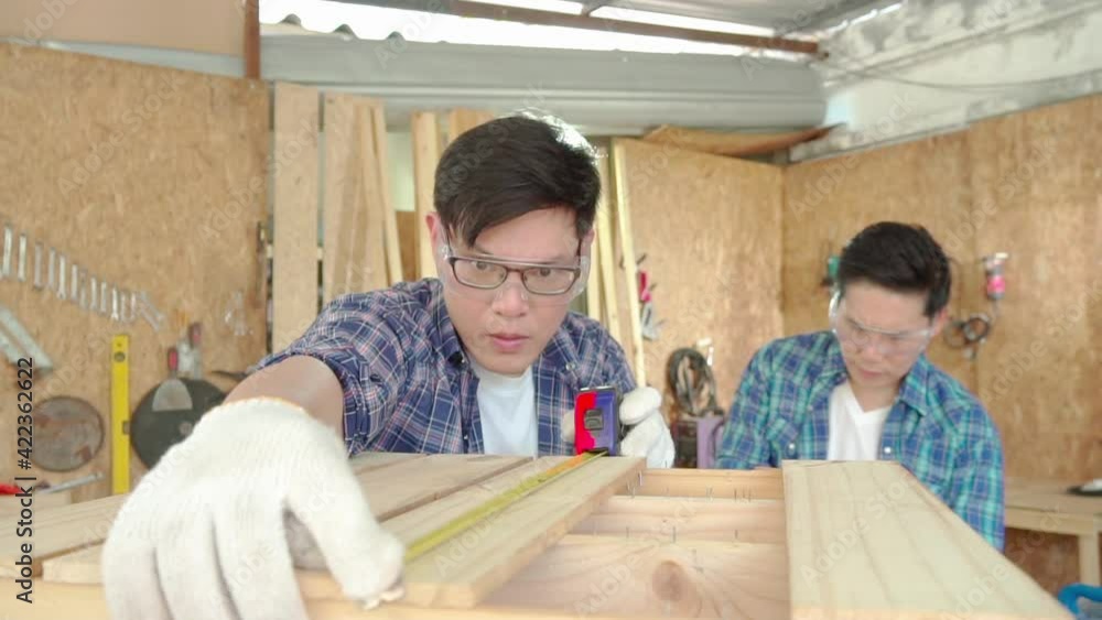 Carpenter using a red pencil to draw a line on a blueprint and wood ...