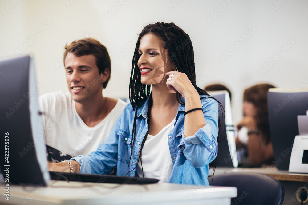 College students sitting in a classroom, using computers during class ...