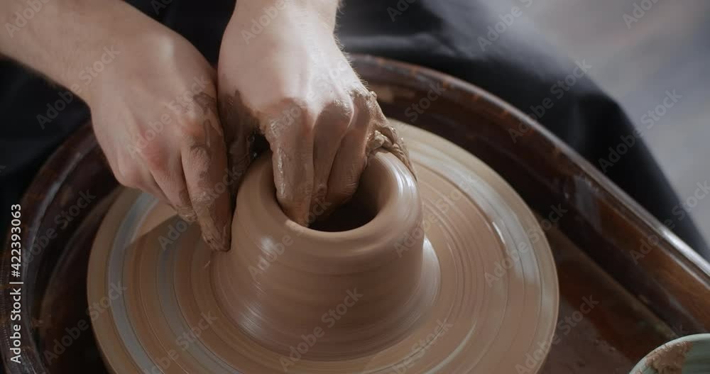 Potter sculpts a jug from red clay on a potter's wheel, pottery ...