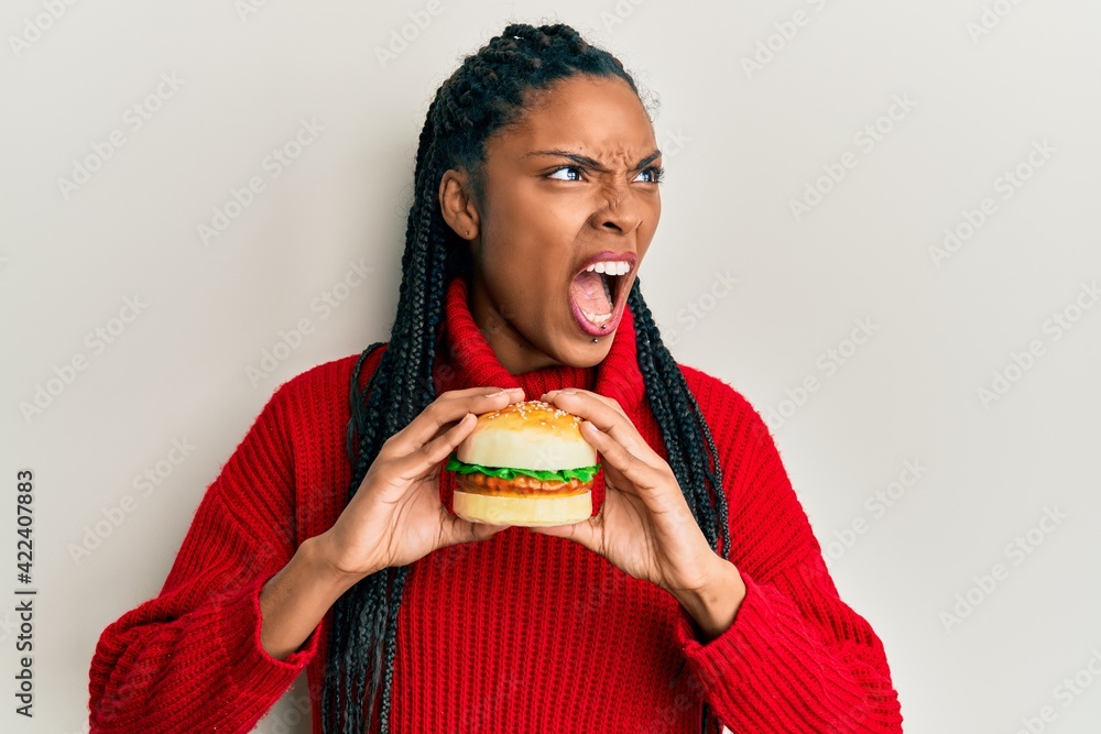 African american woman with braids eating hamburger angry and mad ...