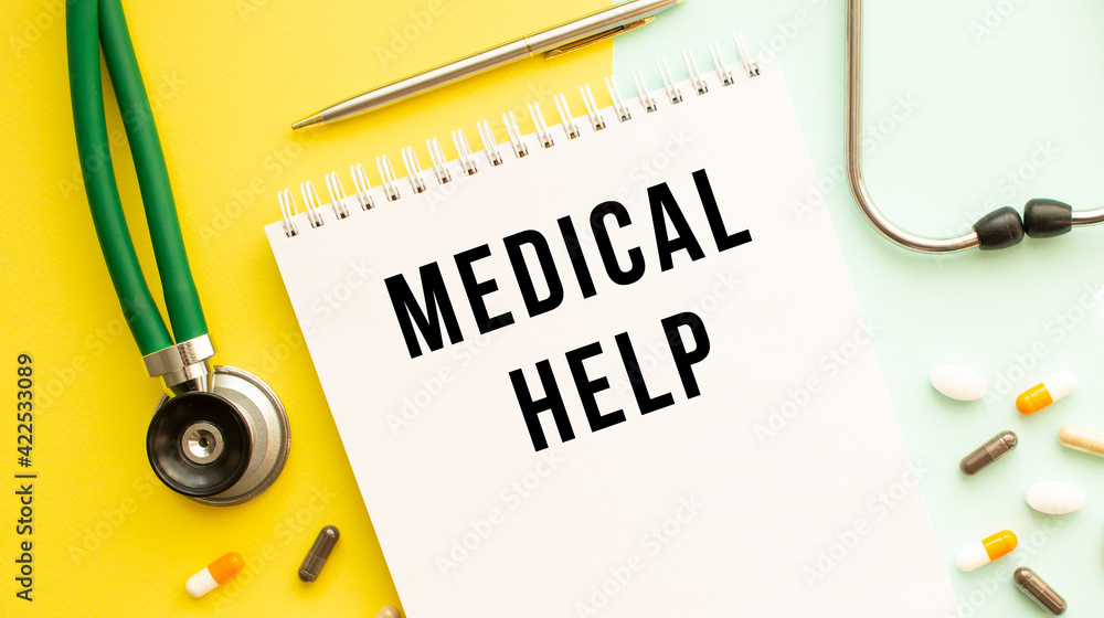 MEDICAL HELP is written in a notebook on a color table next to pills ...