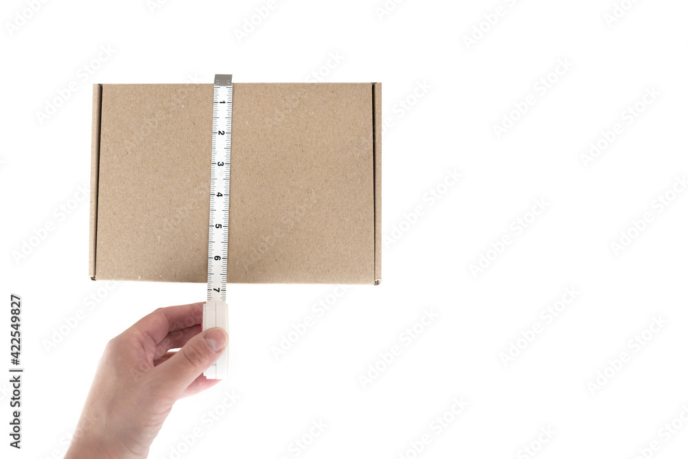 hand using a tape measure measures a cardboard box against white ...