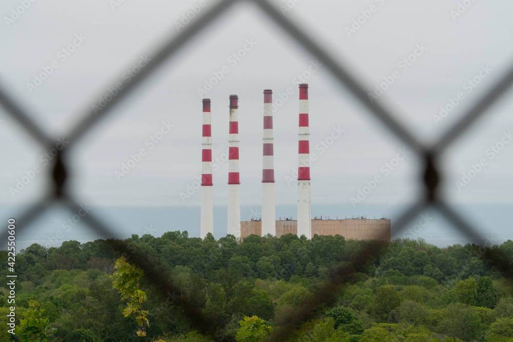 View of tall smoke stacks on power plant through blurry chain link ...