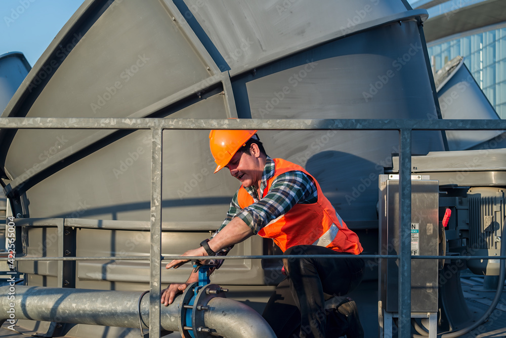 worker in industry. worker open valve of cooling tower on blue sky ...