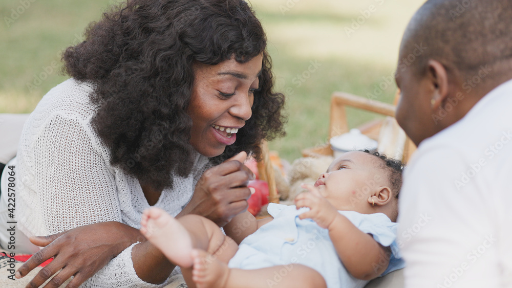 African American family Parents take care of cute baby in garden of ...