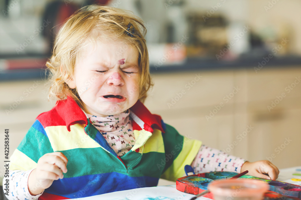 Sad crying baby girl learning painting with water colors. Little ...