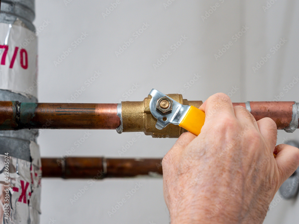 Plumber turning water shut off valve. Copper plumbing pipe with brass ...