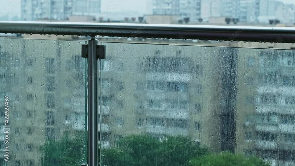 Raindrops trickle down the glass. Balcony glass close-up during the ...