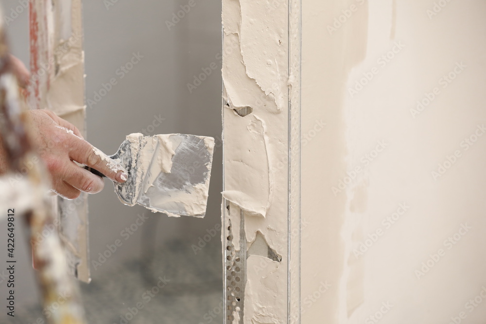 Builder using a trowel to add plaster. Plastering wall with putty-knife ...