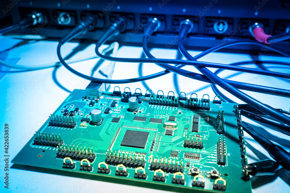 PCB testing. Printed circuit board is connected to tester. Several ...
