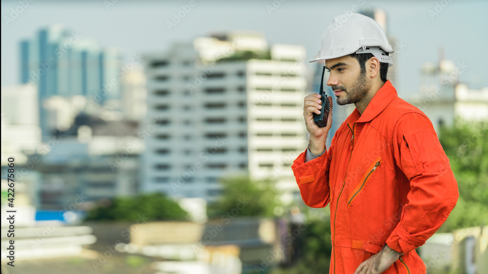 chief engineer using communication radio standing on rooftop of urban ...