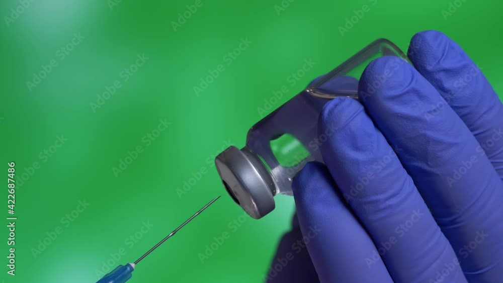 Health doctor dials vaccine into syringe with needle on green ...