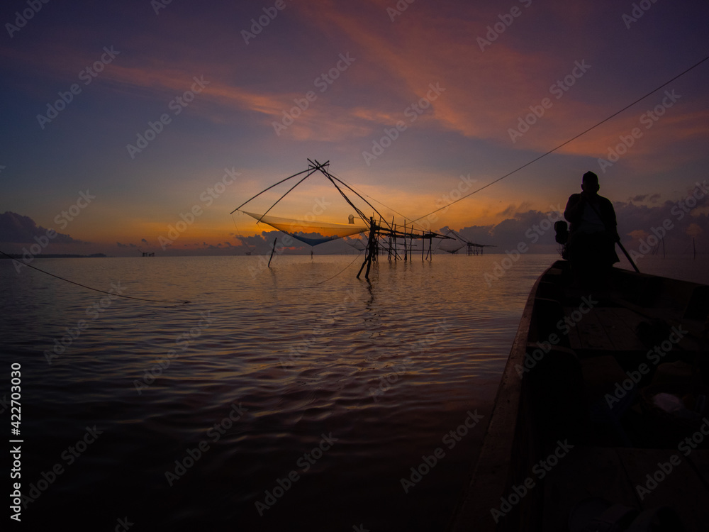 Silhouette photo of fisherman trap fish in front of sunrise scene at ...