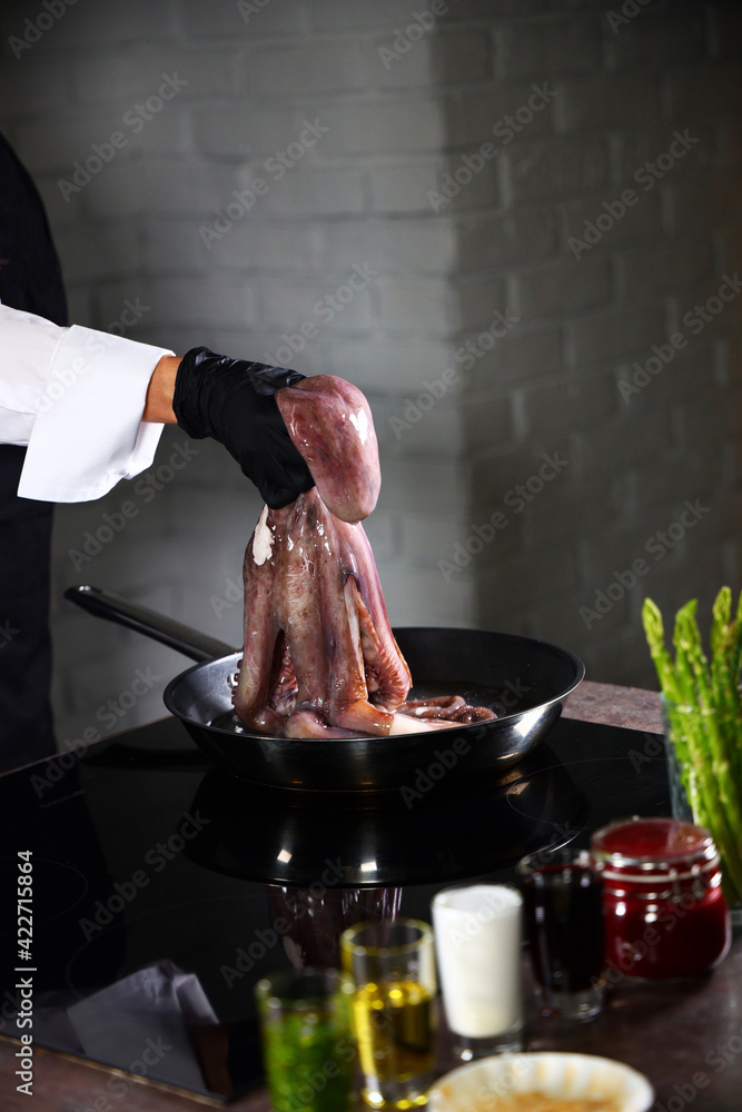 Cook holds the octopus over the pan. Cooking an octopus dish. Seafood ...