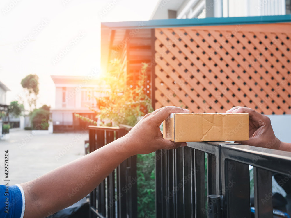 Postman delivering package of goods to home with smile and happy face ...