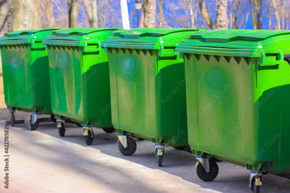 Large green plastic trash cans on city street. Containers on wheels ...
