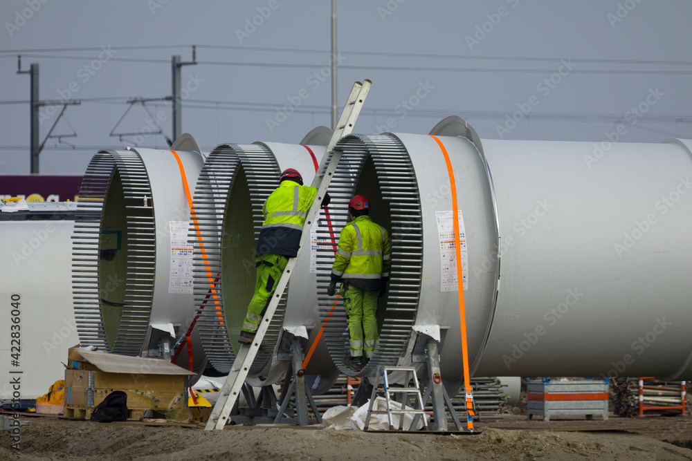 Construction workers preparing the rotor blades of a new wind turbine ...