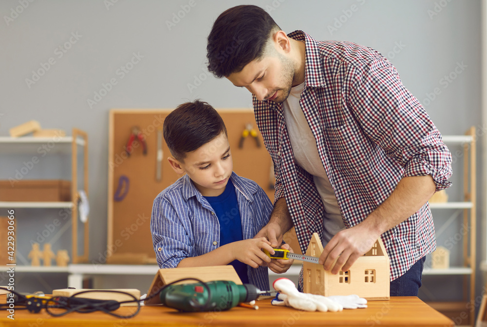 Adult man teaching little boy to work with wood. Serious child and ...
