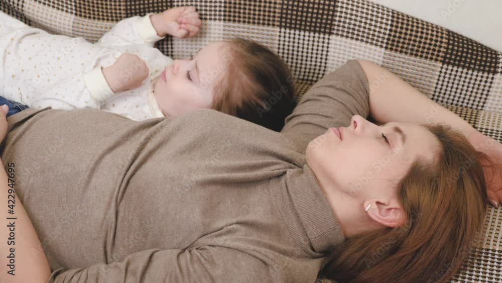 Mom and her little daughter are lying on the couch trying to sleep, mom ...