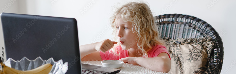Foto de Young girl eating food and watching cartoons on laptop. Child ...