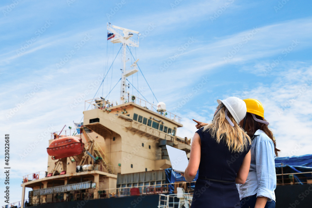 lady workers in shipyard for ship repair or maintenance, male hand holding tablet on floating ...