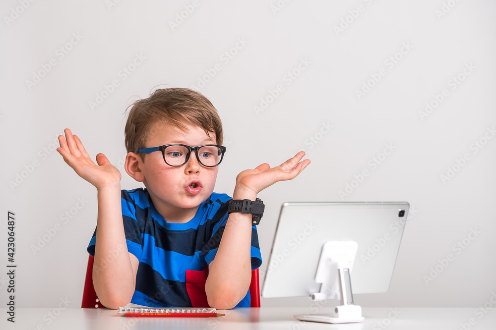 Kid boy shrug. student Child boy in glasses with a tablet in his hand ...