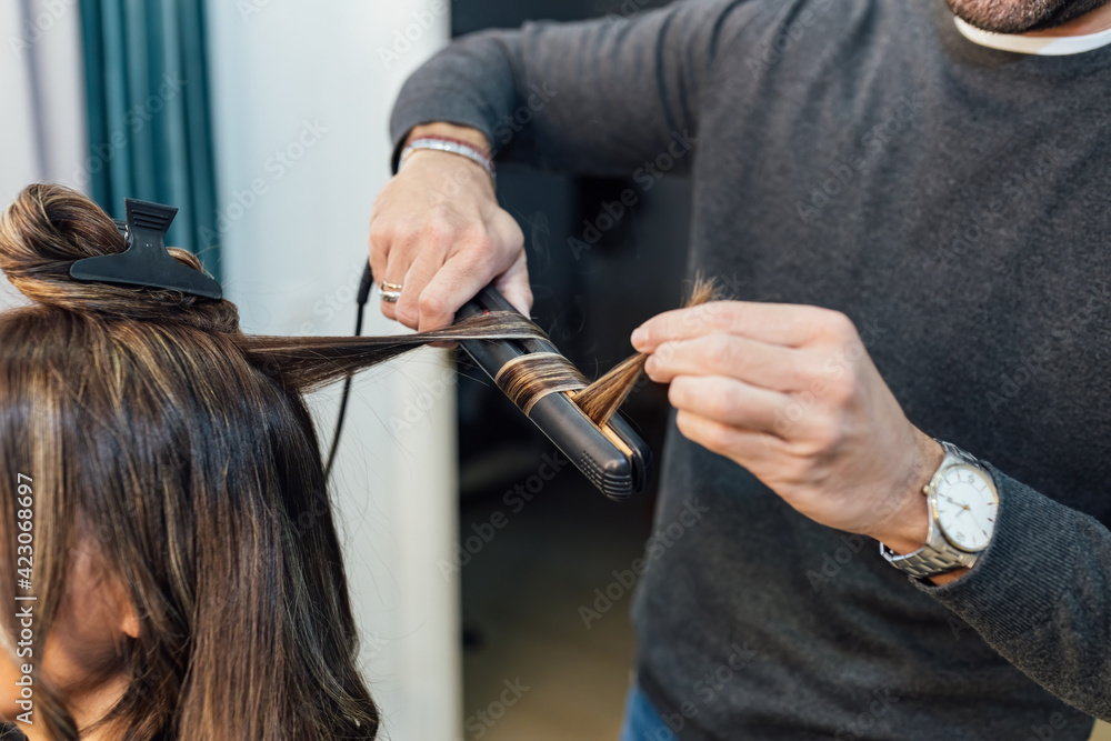Crop unrecognizable male stylist in casual clothes using hair ...