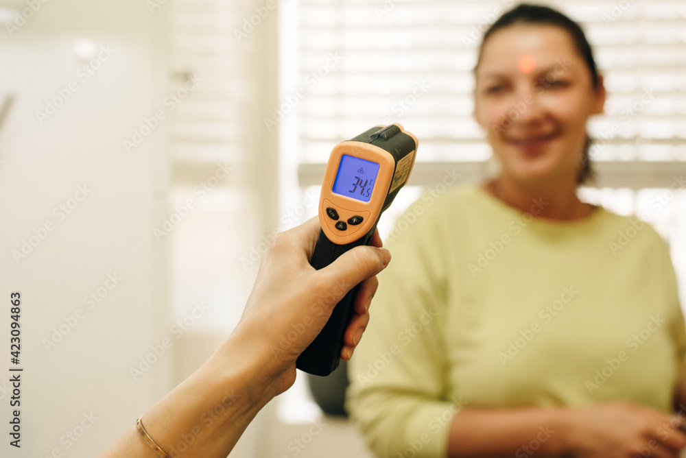 A Doctor checking a woman's temperature with a censor thermometer check ...