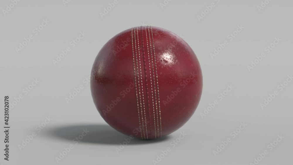 Side on view of a 3D cricket ball slowly rolling on the spot. Shiny red ...